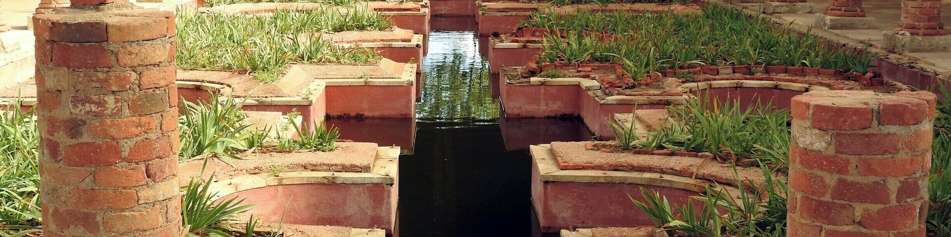 Sítio histórico com estruturas de tijolo e um canal central de água.