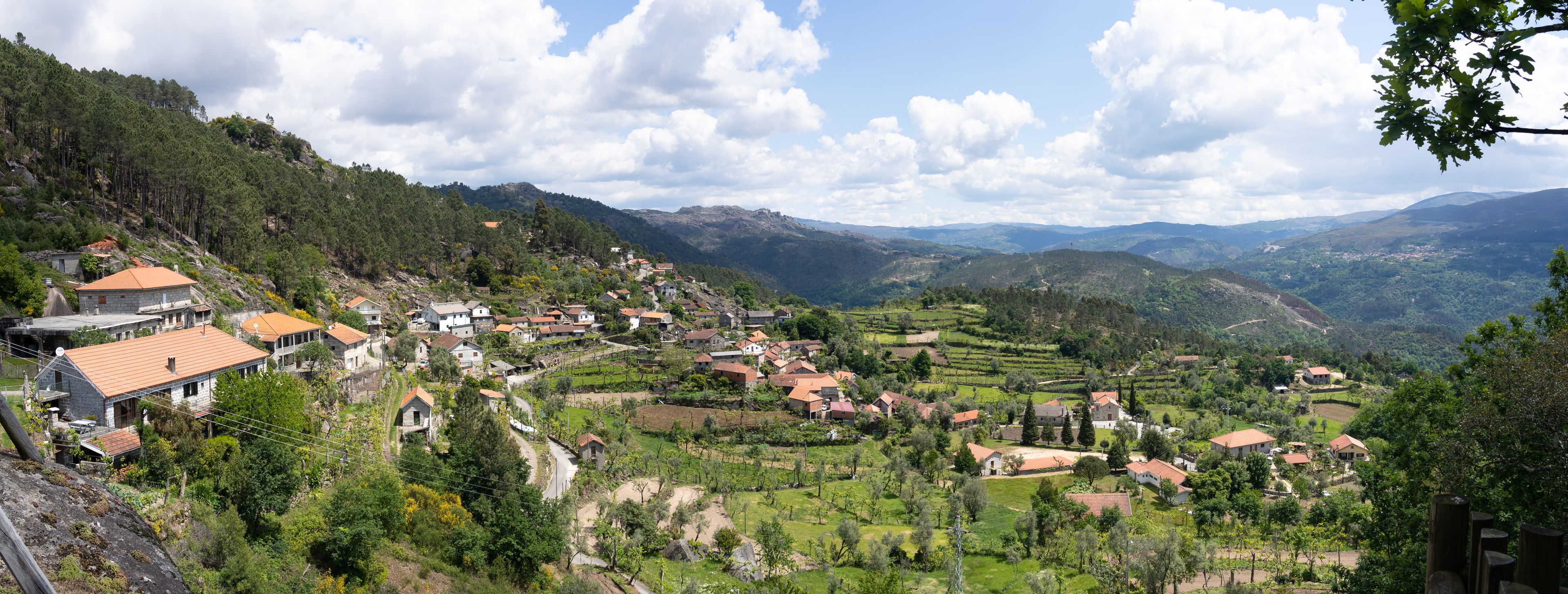 Uma aldeia montanhosa com campos em socalcos e casas tradicionais.