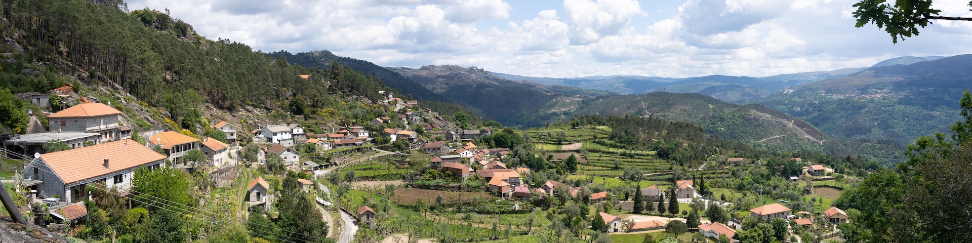 Uma aldeia montanhosa com campos em socalcos e casas tradicionais.