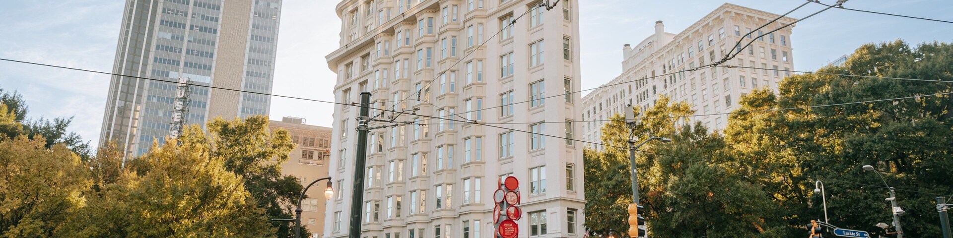 Rua urbana com edifícios históricos, um arranha-céu moderno e uma placa de rua indicando Locke St.