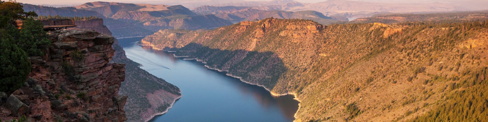 Um cânion com rio, penhascos íngremes e uma cordilheira ao longe.