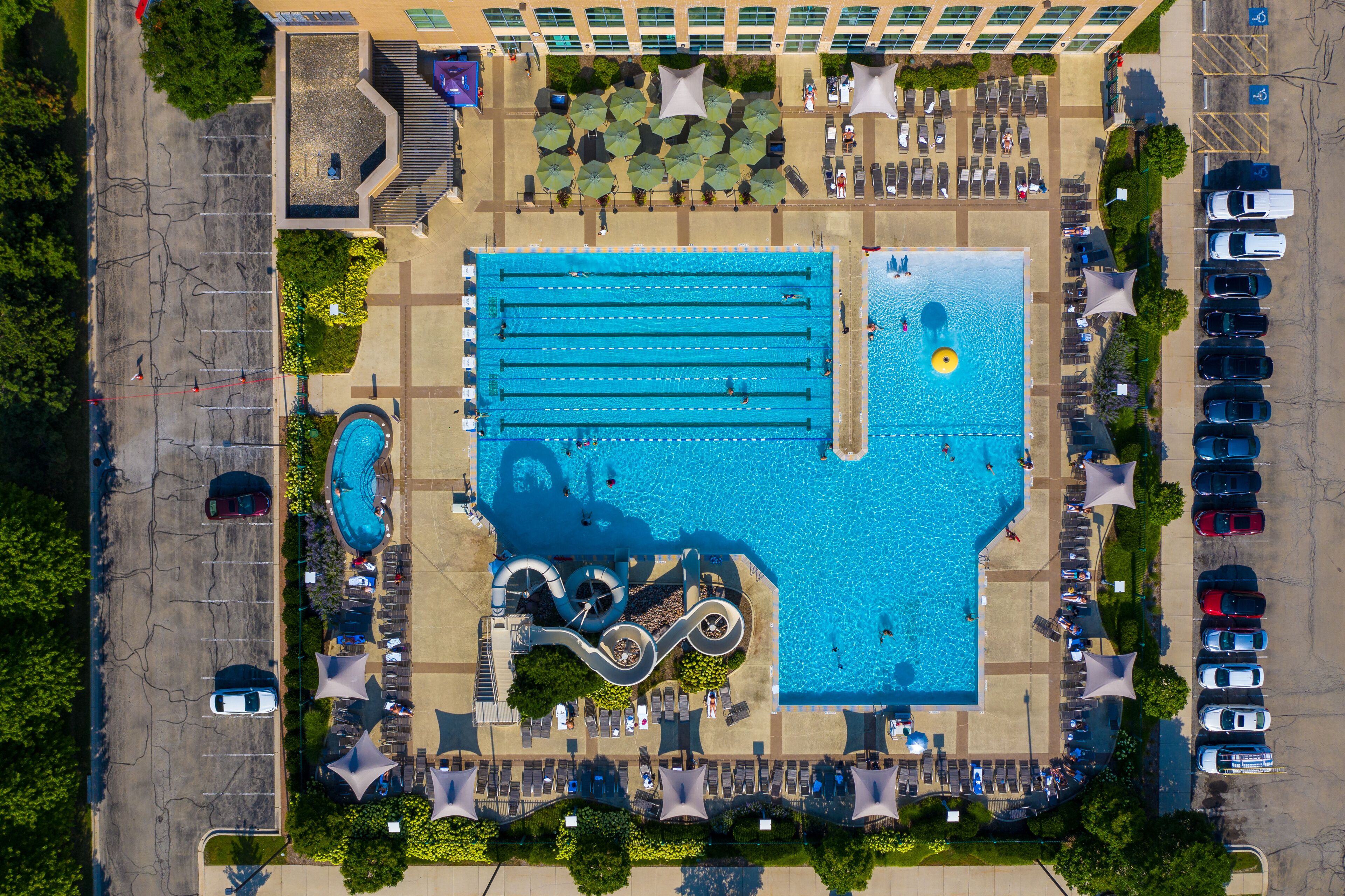 Vista aérea de um complexo de piscinas com várias pistas, um toboágua e áreas de lazer ao redor.