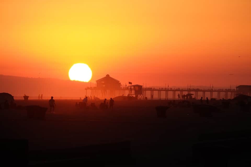 Um pôr do sol sobre um píer, com pessoas caminhando.