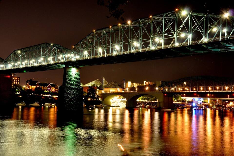 Uma ponte bem iluminada à noite, com reflexos na água.