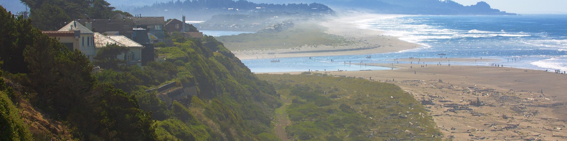 Paisagem costeira com praia, falésias e casas numa encosta.