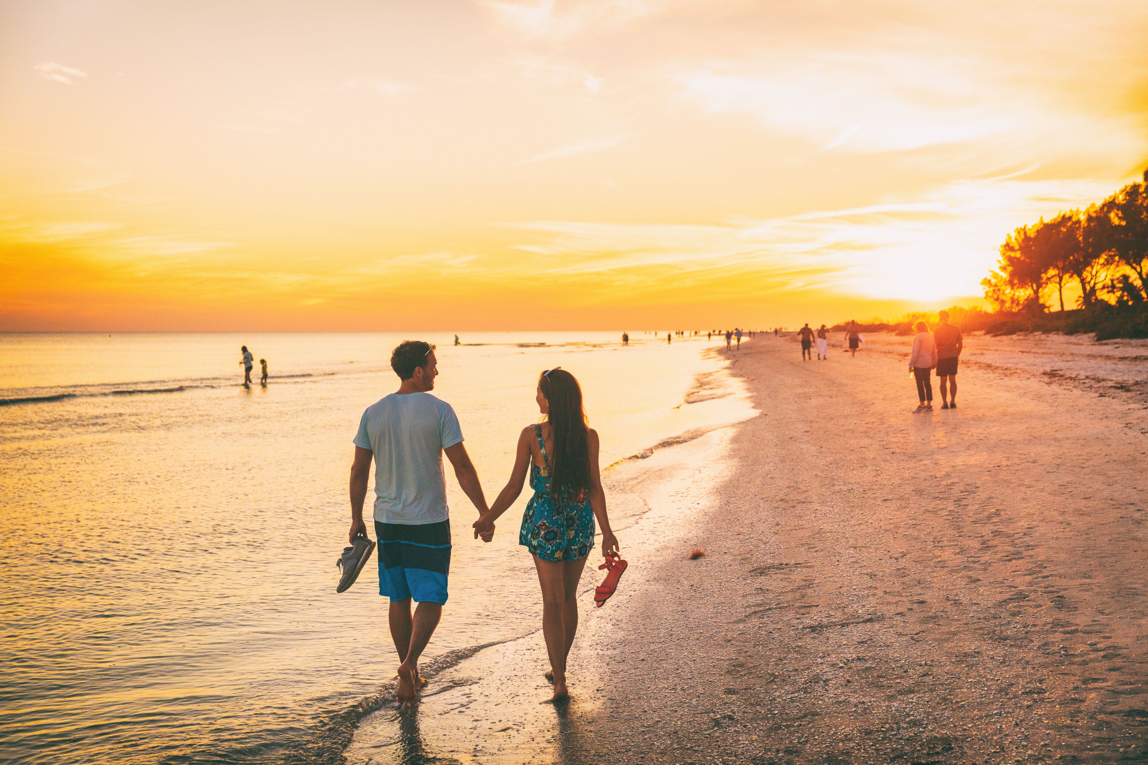 Um casal caminhando na praia durante o pôr do sol.