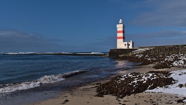 Um farol à beira-mar com ondas quebrando na costa.