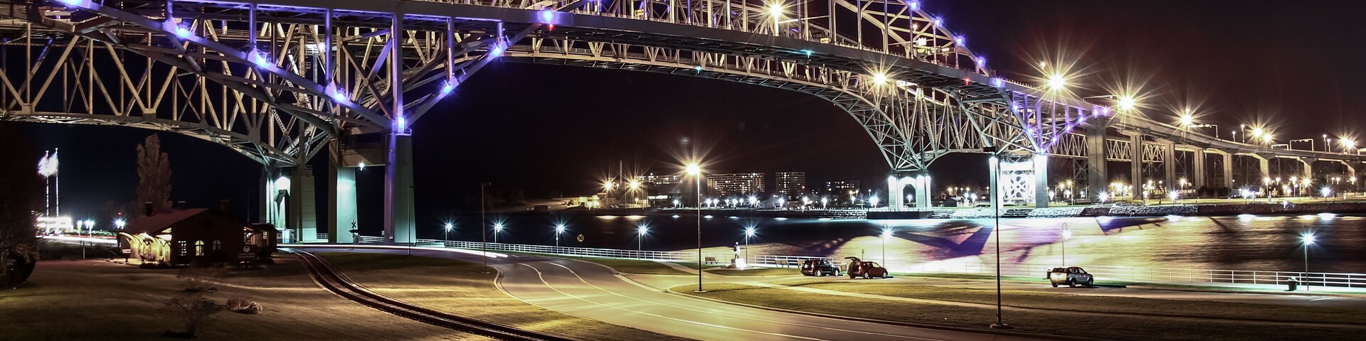 Uma ponte bem iluminada à noite, com um rio abaixo.