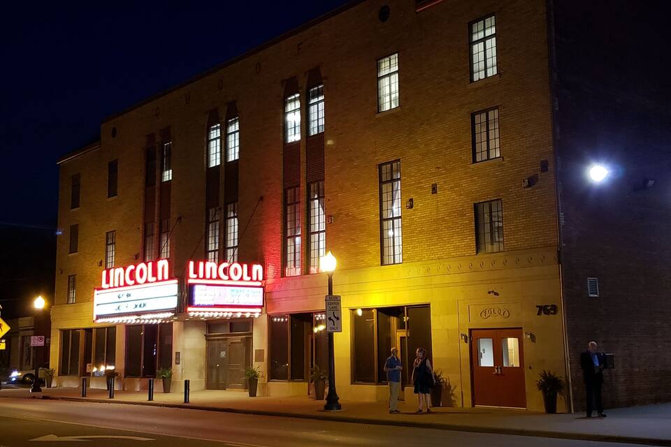 Um teatro com letreiros de neon 'Lincoln', uma calçada e uma rua.