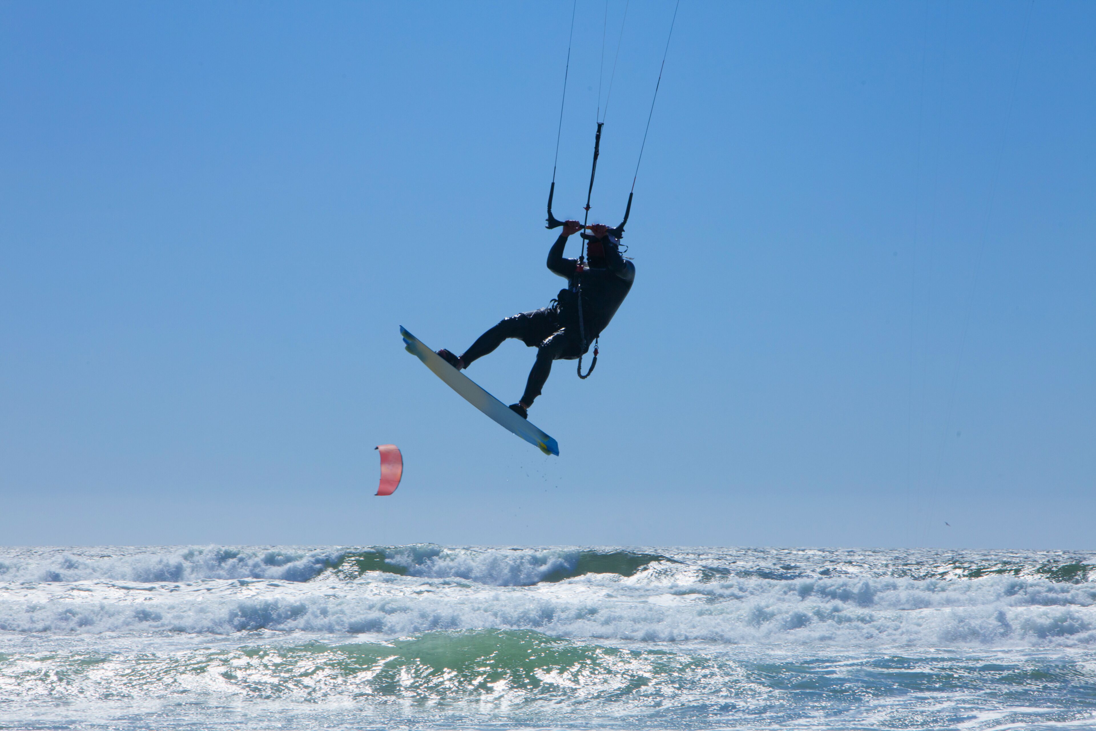 Uma pessoa praticando kitesurf sobre o oceano, com ondas.