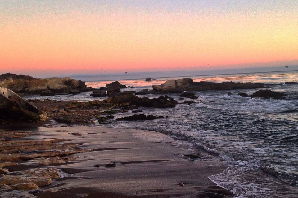 Uma costa rochosa com ondas ao pôr do sol.