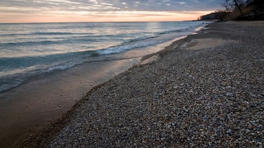 Uma praia de seixos com ondas ao pôr do sol.