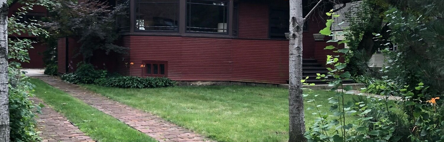 Uma casa de dois andares com telhado inclinado e um caminho de tijolos que a leva.