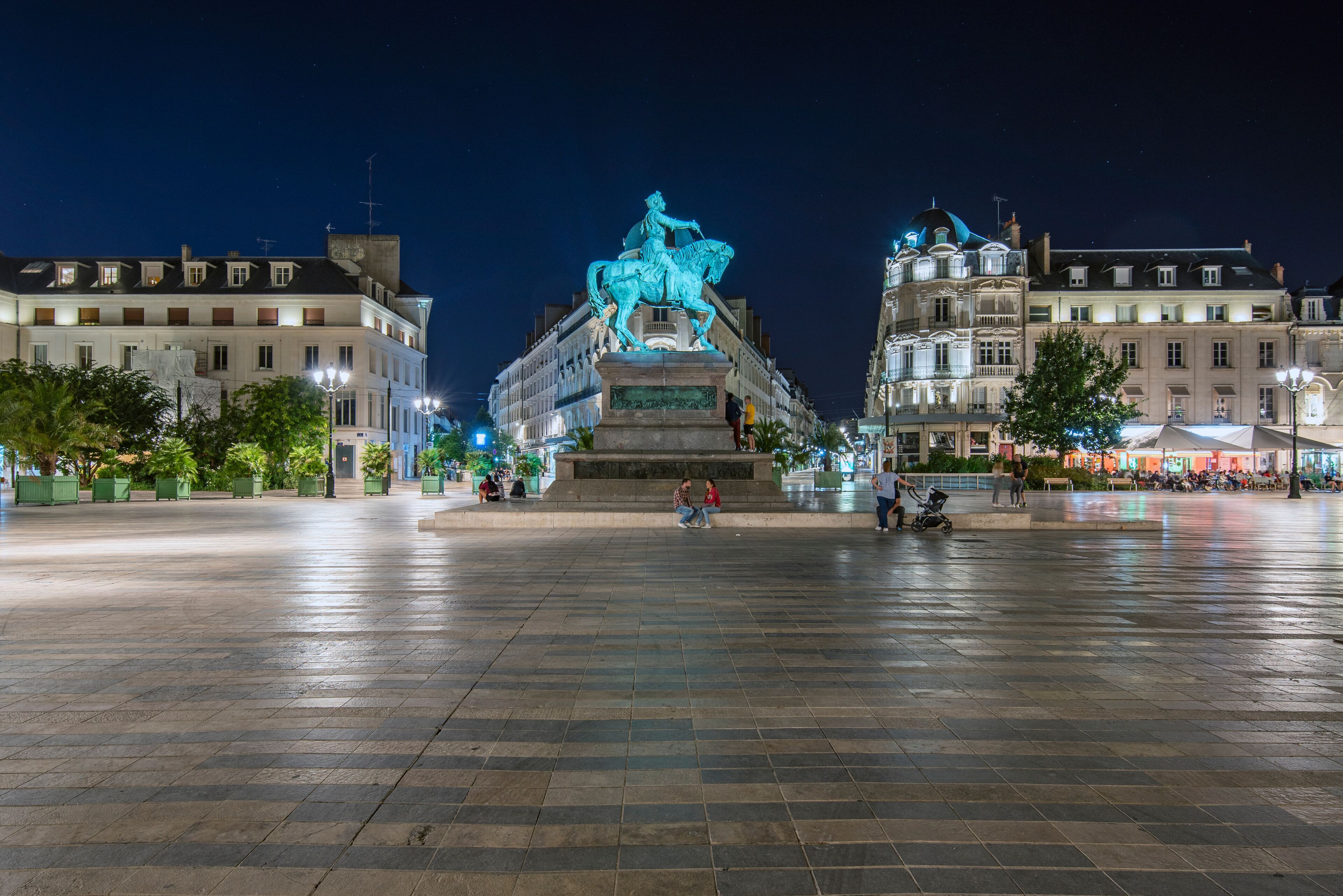 Uma praça com uma estátua de um homem a cavalo, rodeada por edifícios históricos.