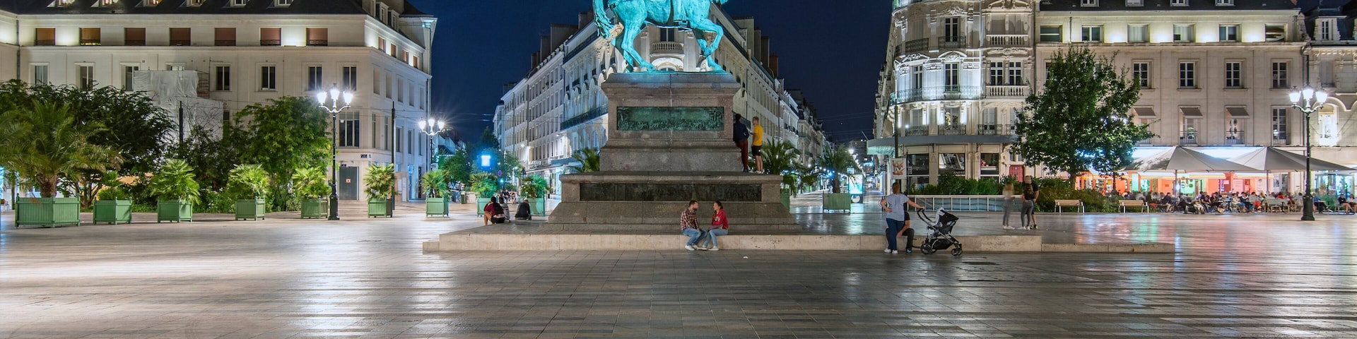Uma praça com uma estátua de um homem a cavalo, rodeada por edifícios históricos.