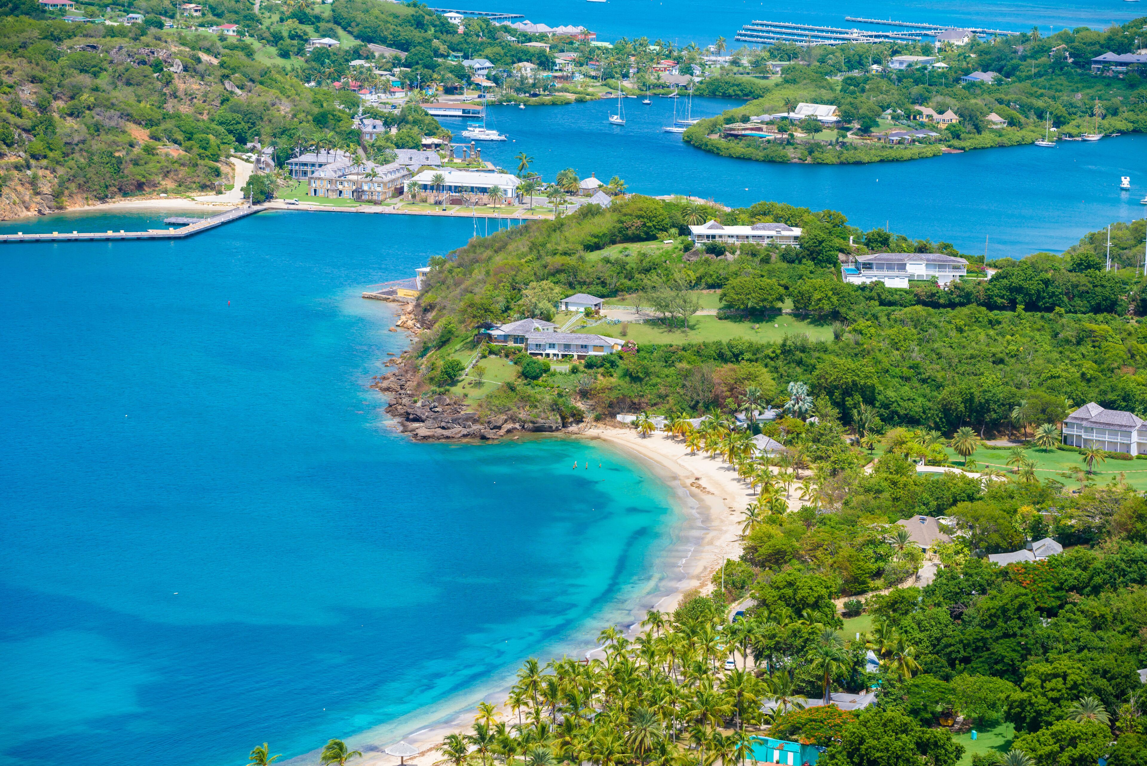 Uma área costeira com águas azul-claras, uma praia de areia e vegetação exuberante.