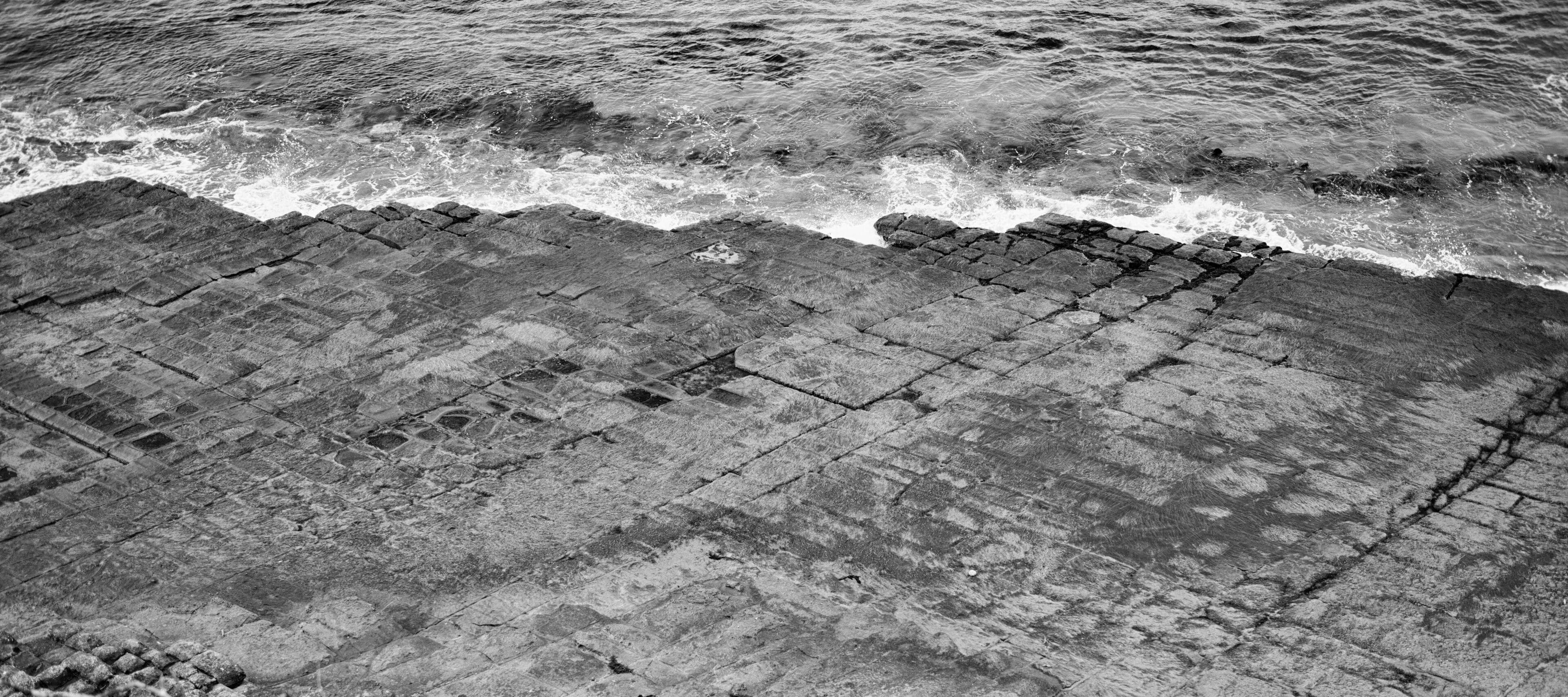 Muro de pedra com ondas quebrando.