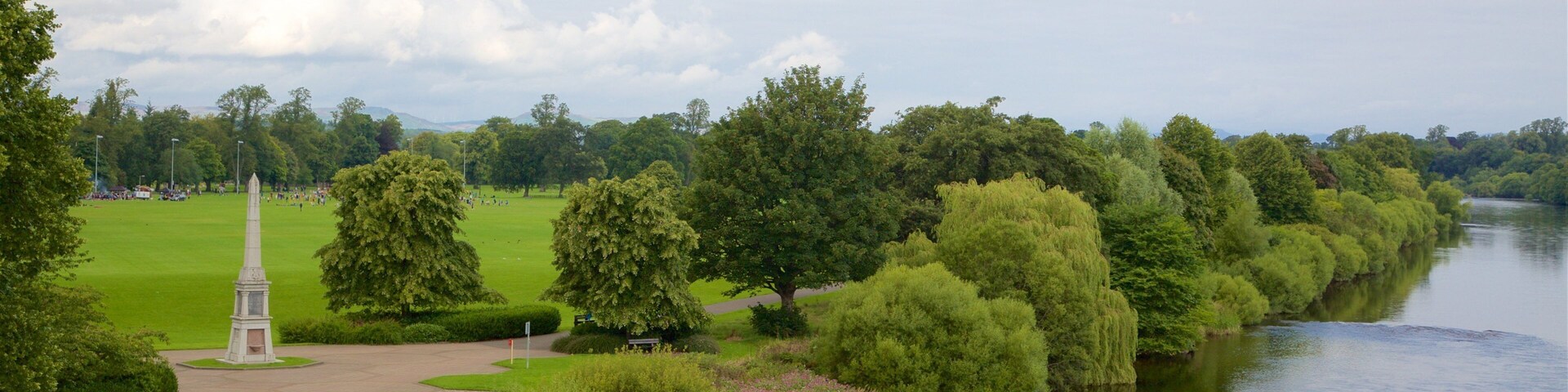 Um rio com vegetação exuberante e um monumento em um parque.
