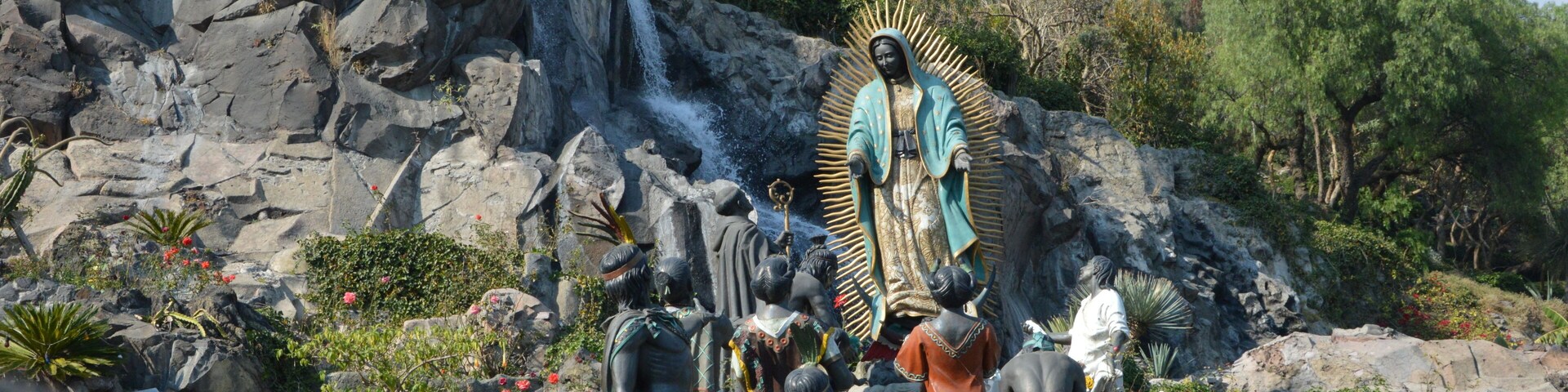 Uma grande estátua de uma figura religiosa cercada por estátuas menores e pedras.