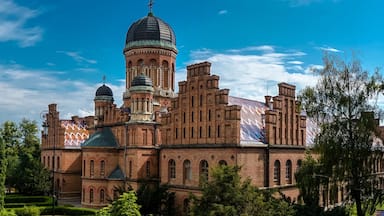 Um edifício histórico com várias torres e cúpulas, rodeado por vegetação exuberante.