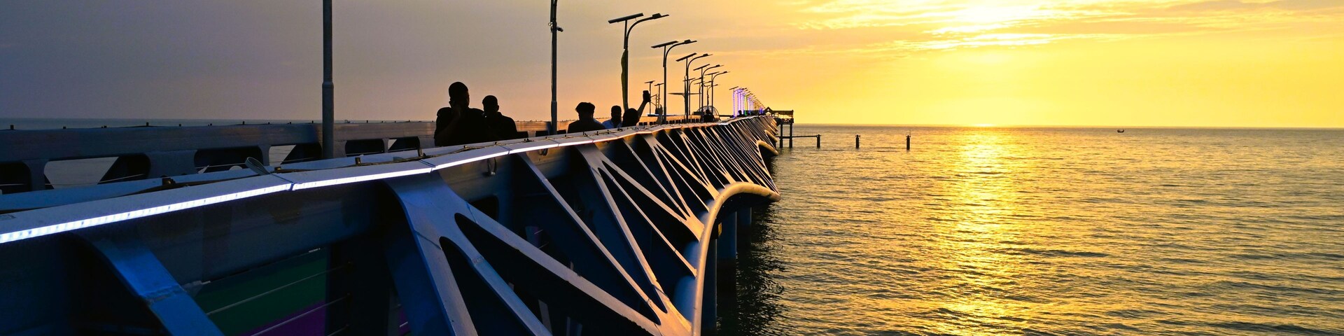Um píer se estendendo sobre a água ao pôr do sol.