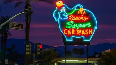 Letreiro de neon do Rancho Super Car Wash contra um céu crepuscular.
