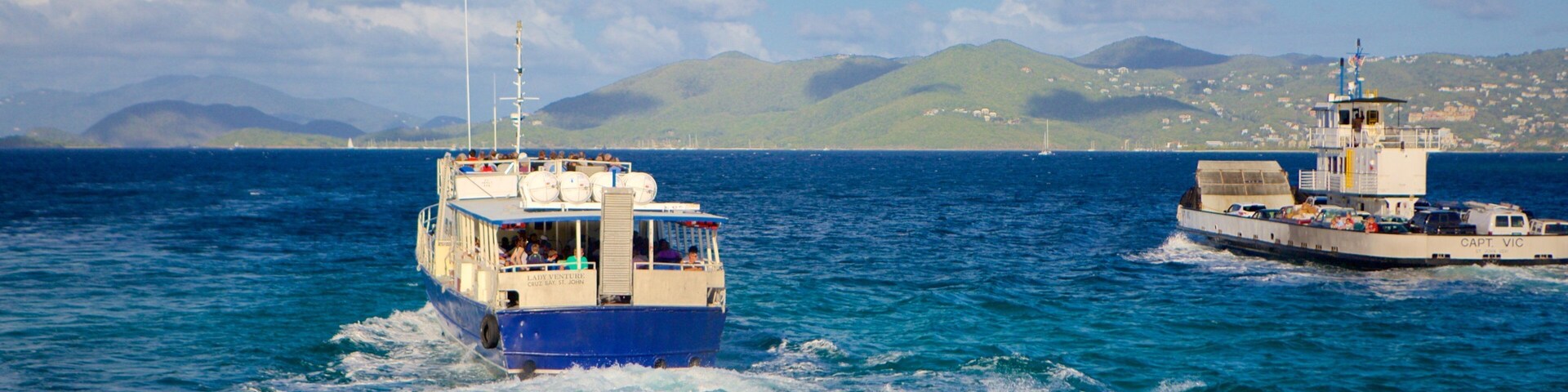 Dois barcos em um mar azul, com montanhas ao fundo.