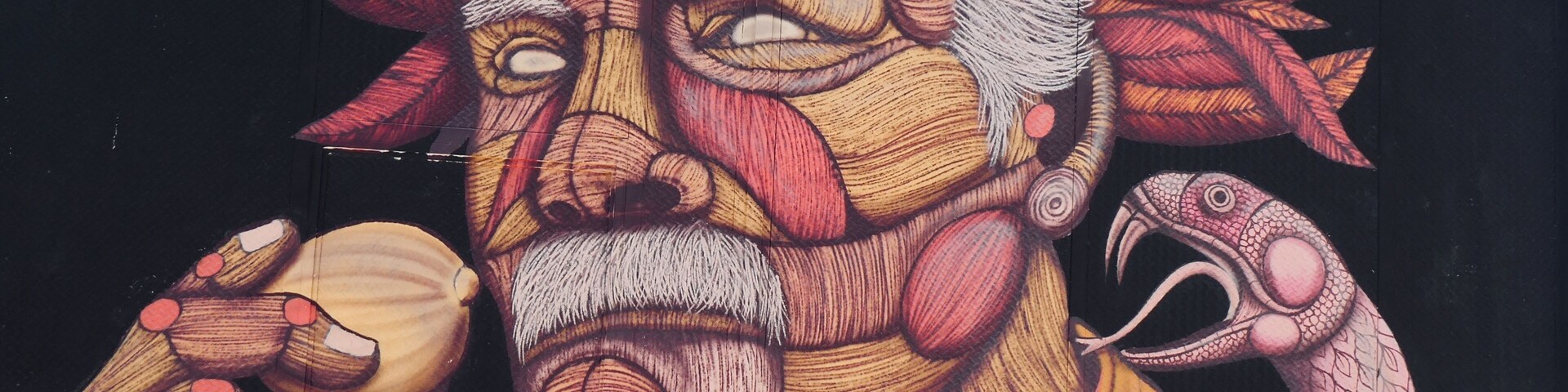 Um mural detalhado com uma figura segurando uma serpente, cercada por folhagem vibrante.