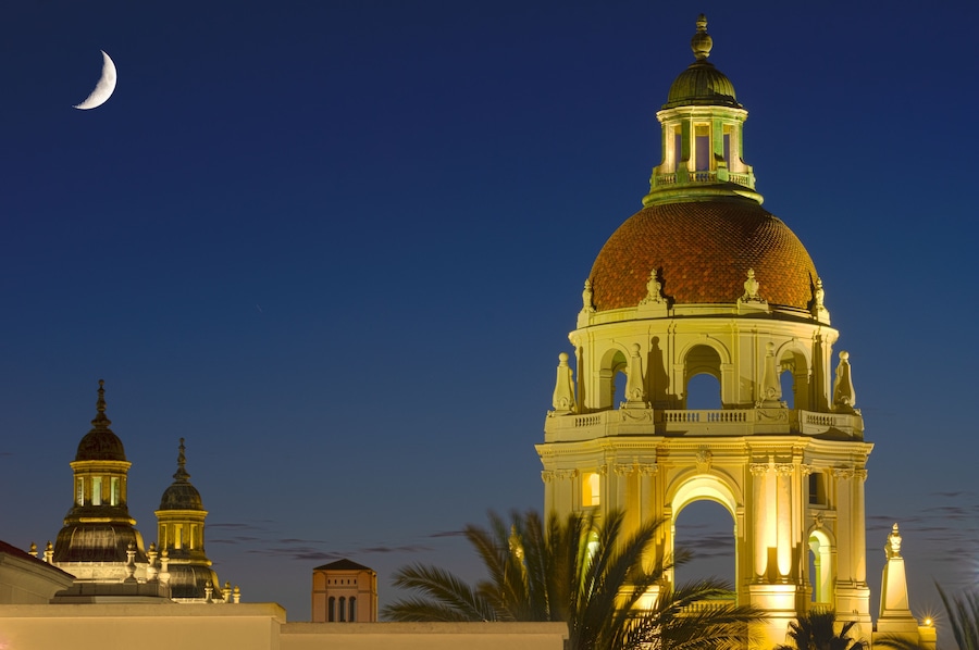 Uma grande cúpula iluminada com estátuas, uma lua crescente e duas cúpulas menores ao fundo.