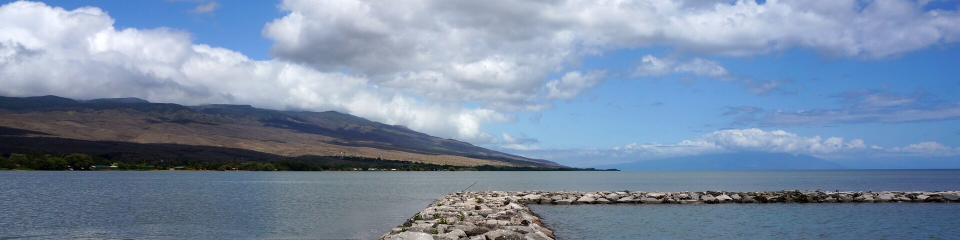 Uma ilha rochosa em um lago, com montanhas ao fundo.
