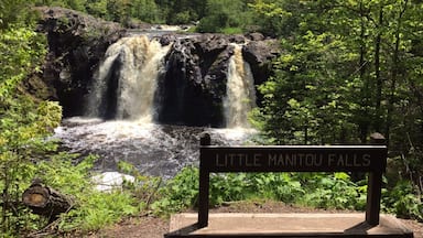 Uma cachoeira identificada como "Little Manitou Falls" rodeada por vegetação exuberante.
